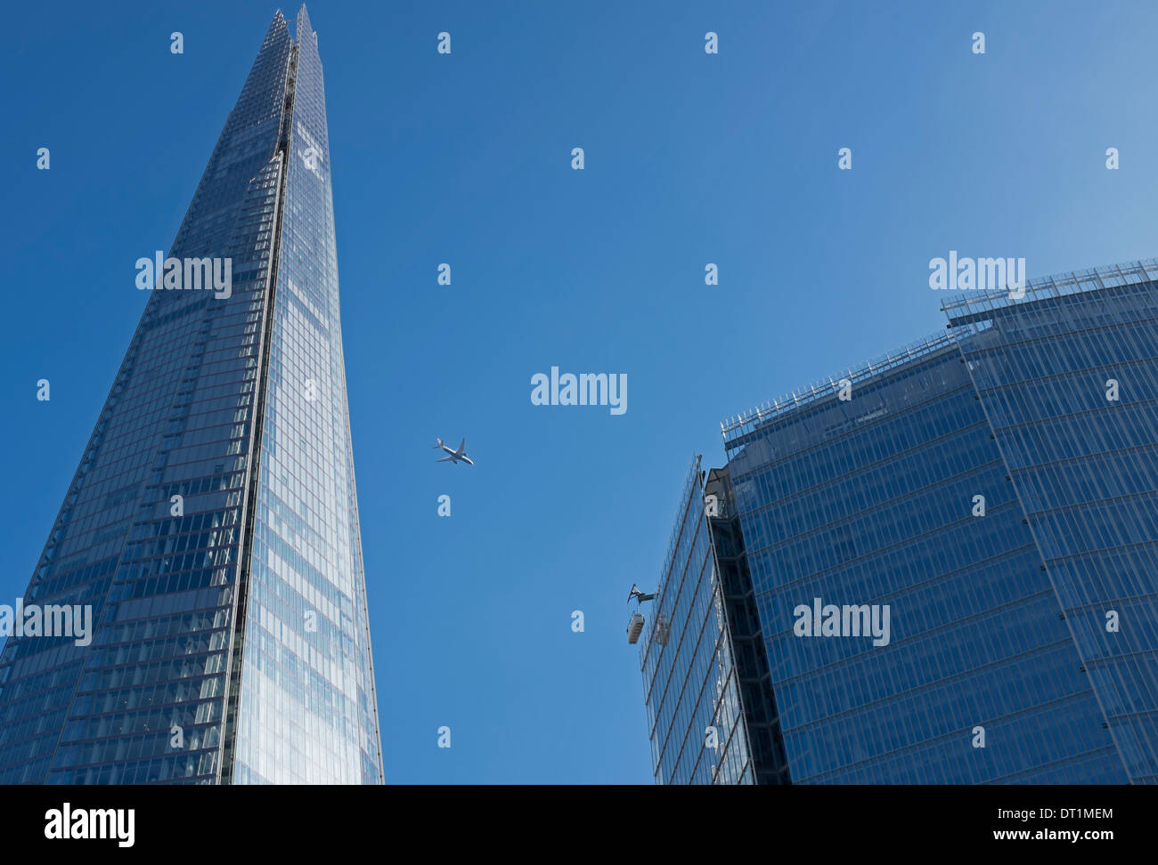 An aeroplane flying between buildings in a blue London sky Stock Photo ...