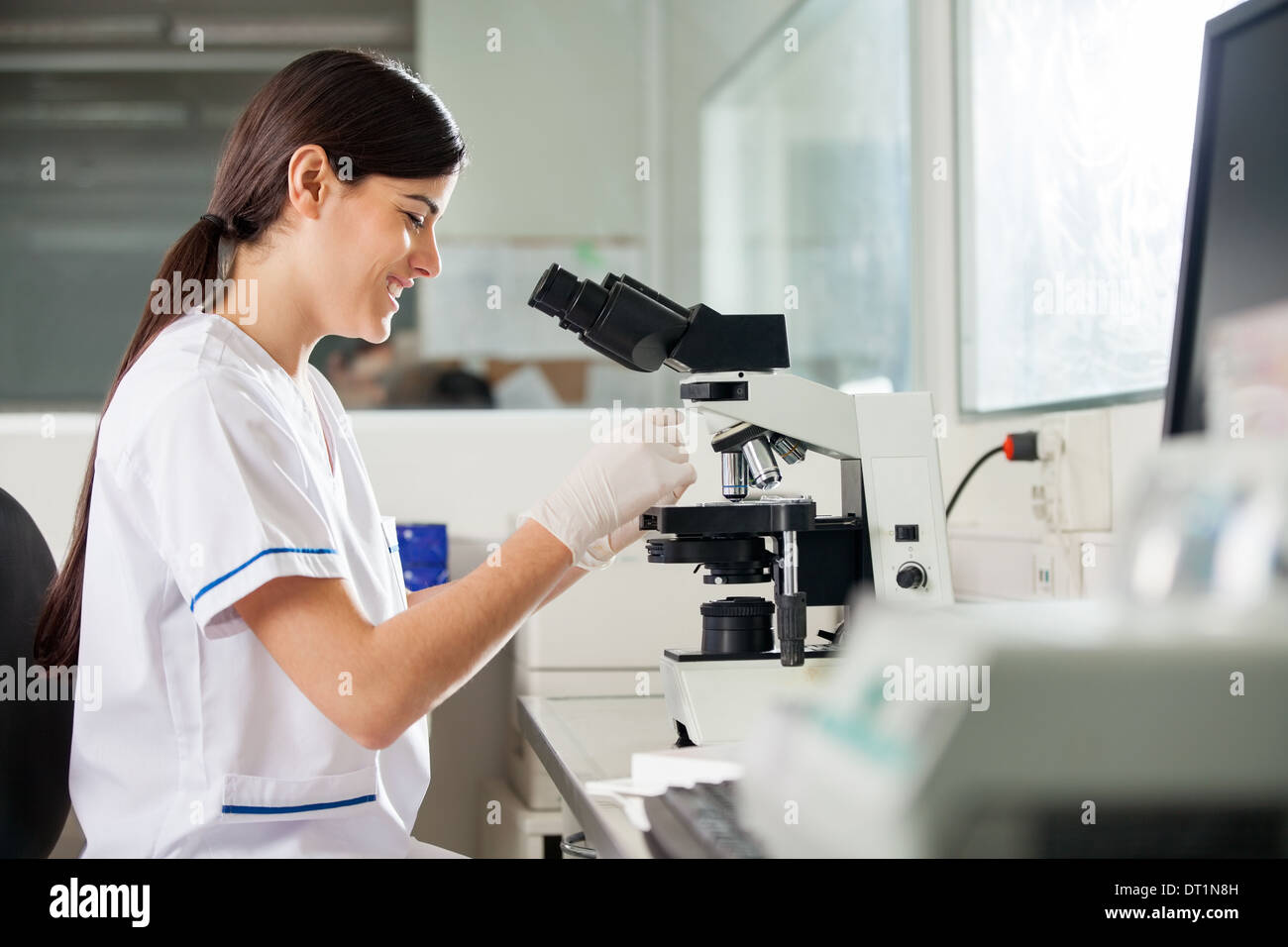 Happy Female Scientist Using Microscope In Lab Stock Photo - Alamy