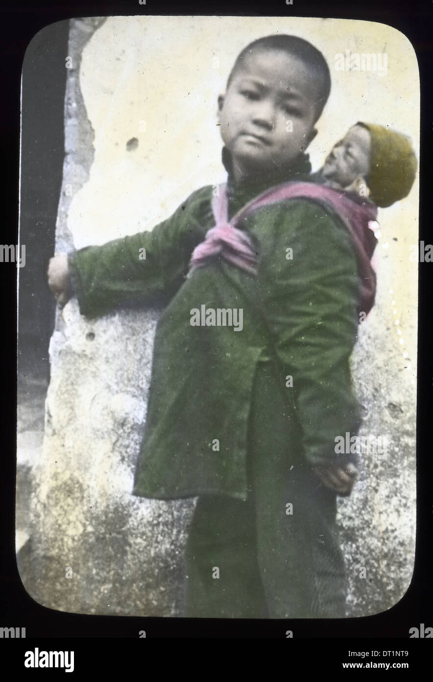 A photograph of a girl carrying a baby on her back in China, taken ...