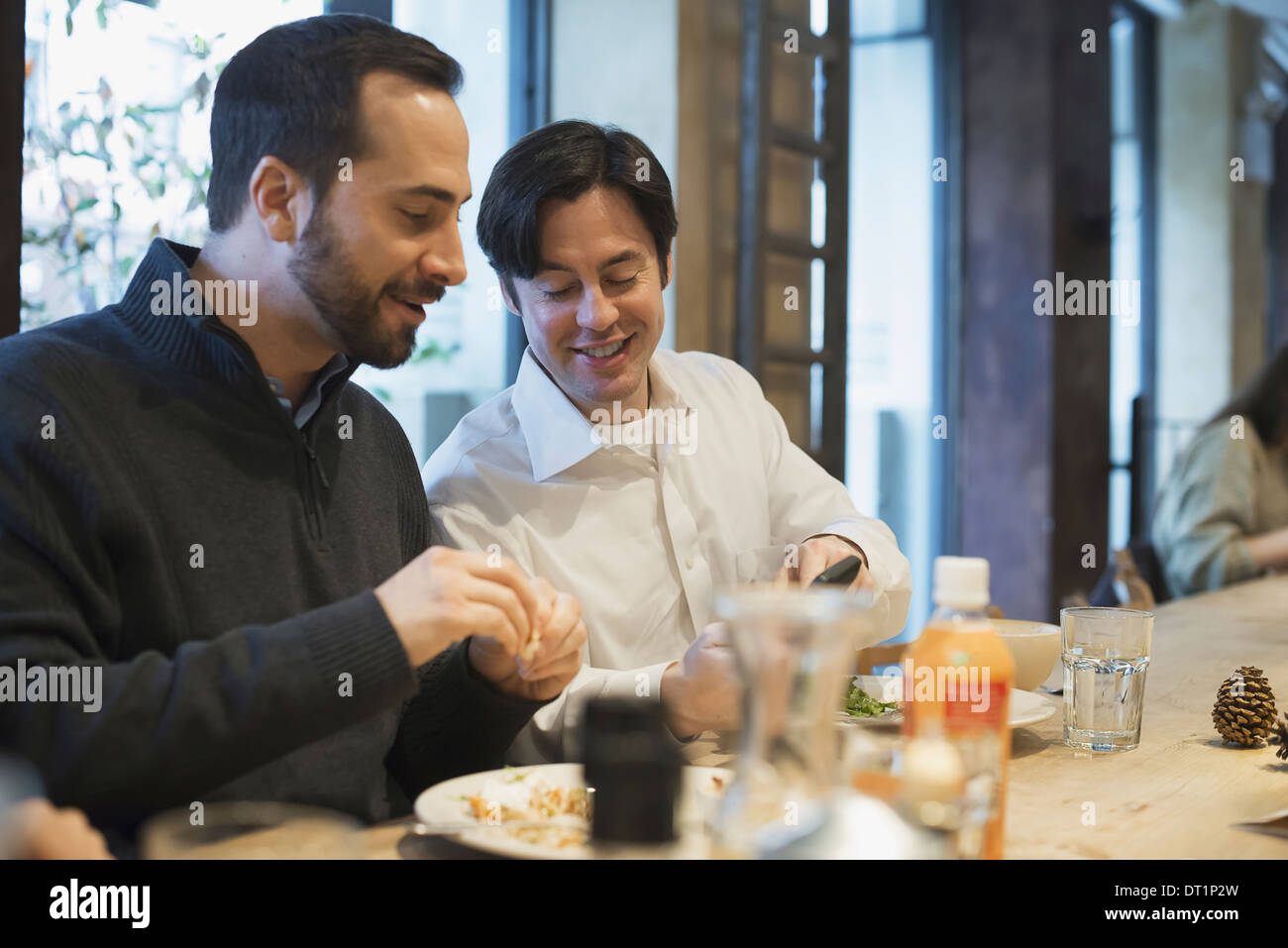 Men sharing text at restaurant table Stock Photo - Alamy