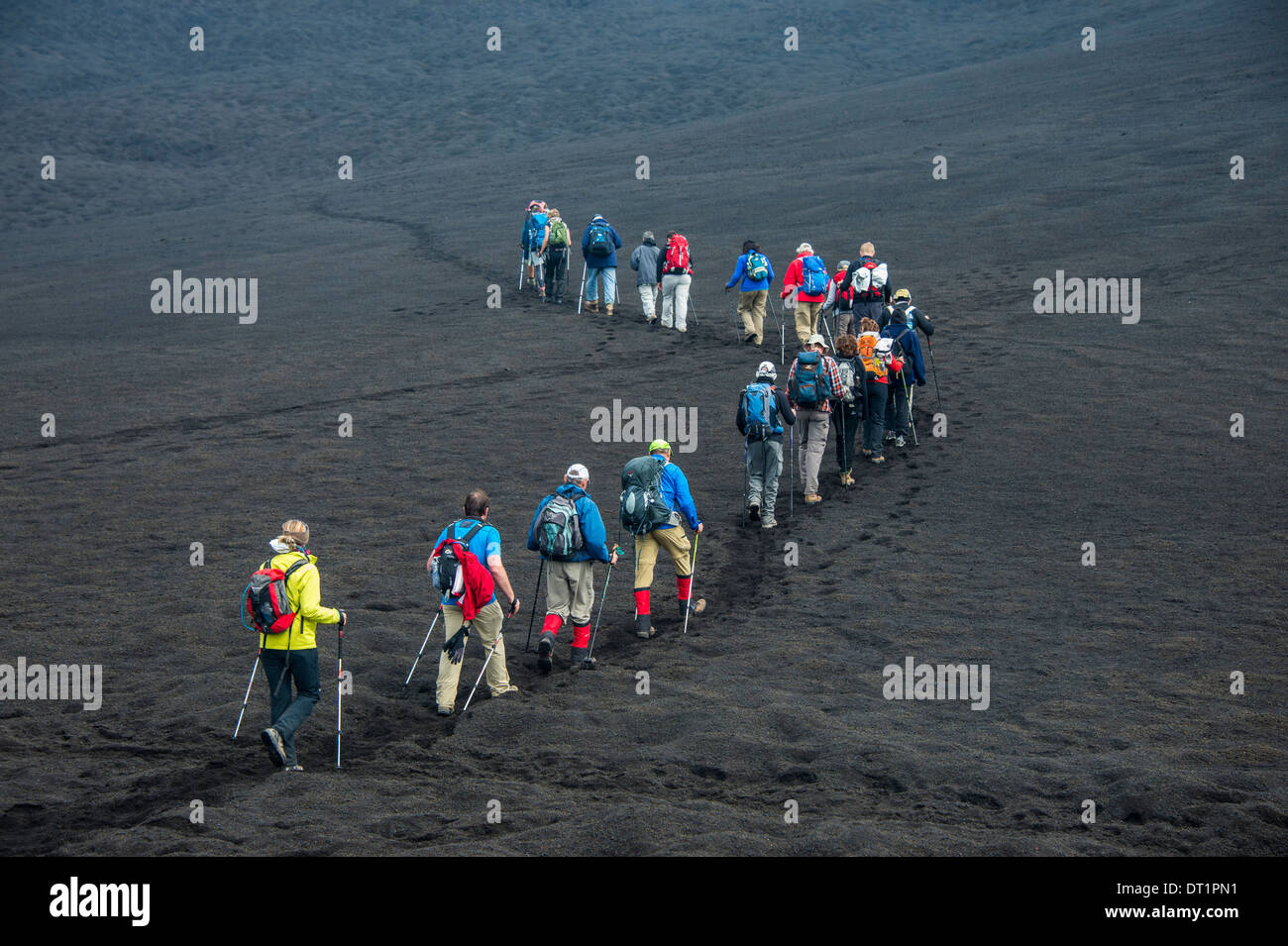 Tourists walking in a line through the lava sands of the Tolbachik ...