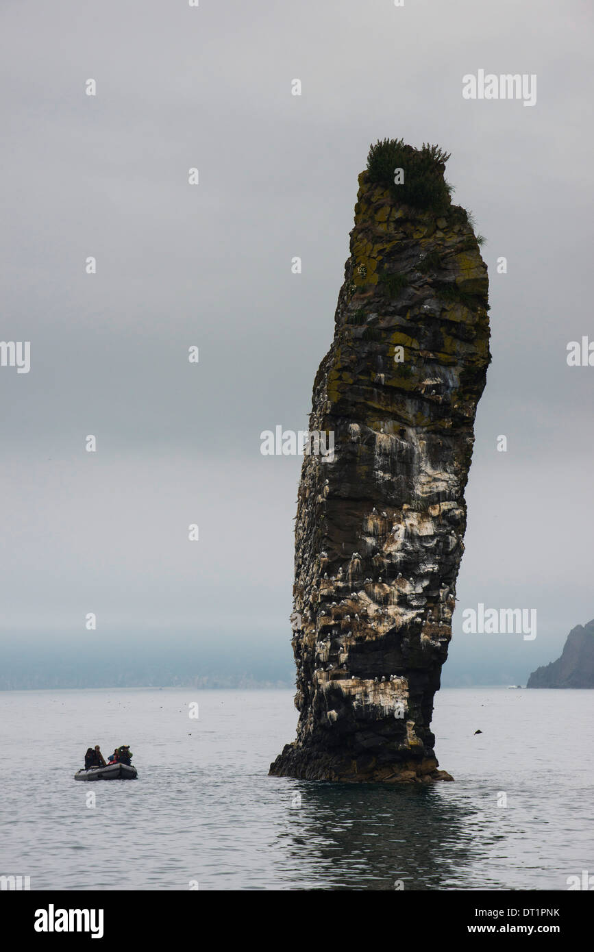 Little tourist boat ships beside a large monolith in the Avacha Bay ...