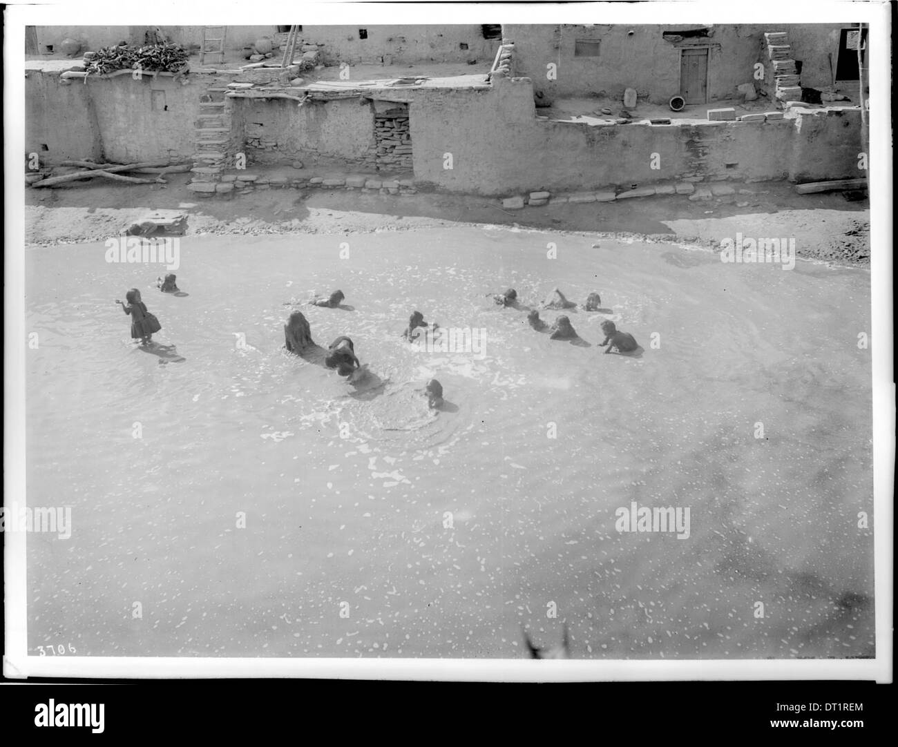 Hopi Indian children playing in a large puddle of rainwater in Oraibi ...