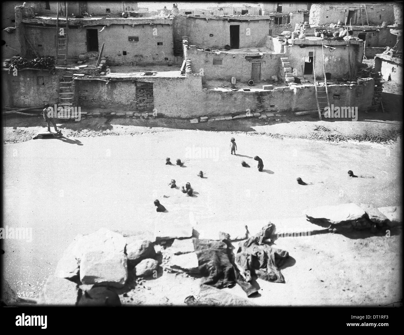 A group of Hopi Indian children is shown playing in a large puddle of ...