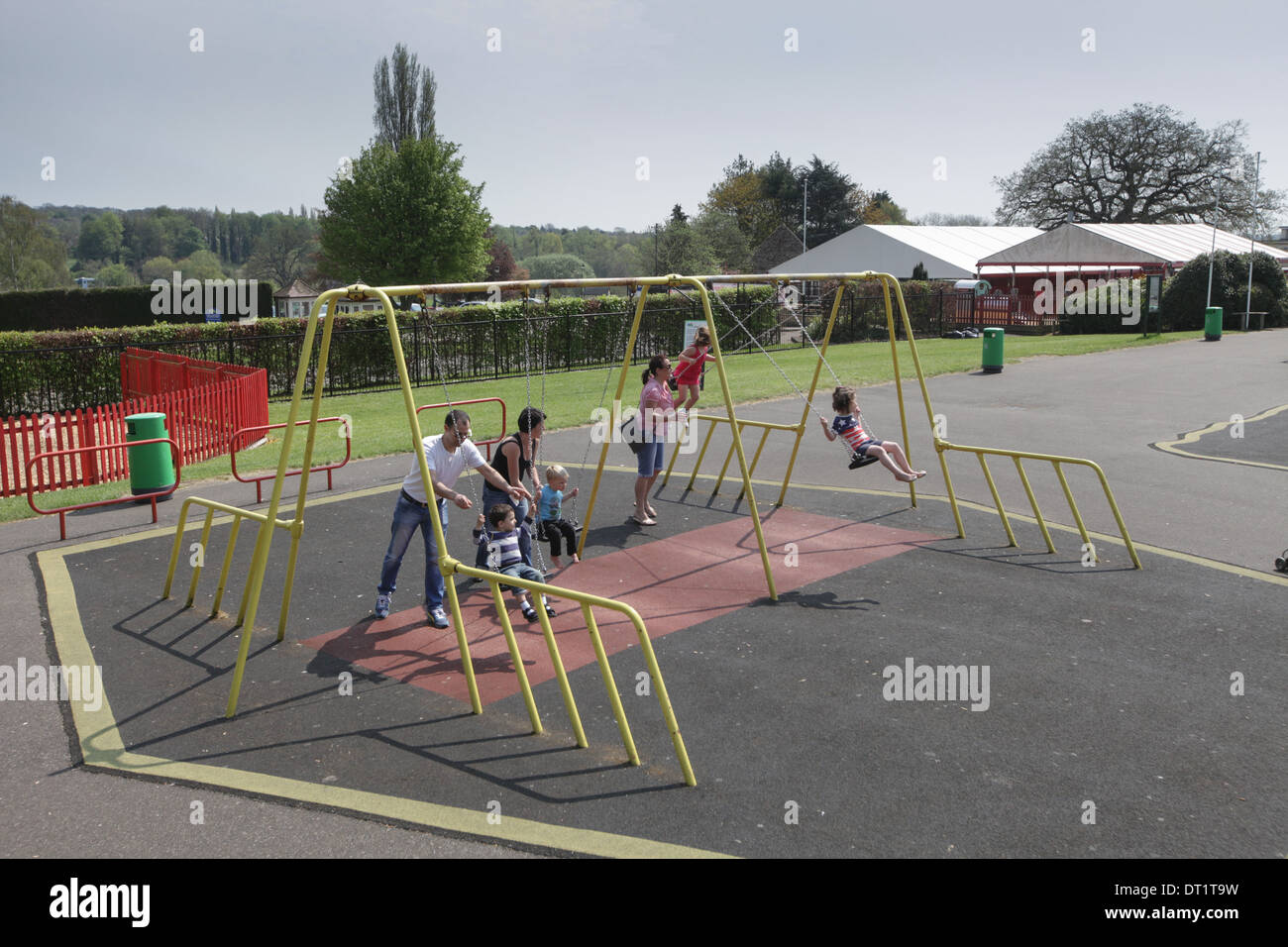 CHILDREN PLAYING ON SWINGS IN WICKSTEAD PARK IN KETTERING,NORTHANTS ...