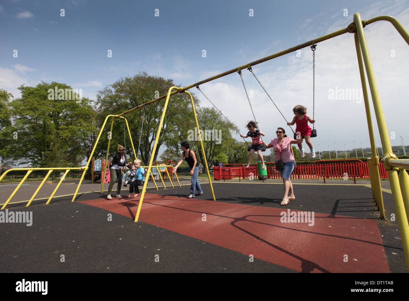 CHILDREN PLAYING ON SWINGS IN WICKSTEAD PARK IN KETTERING,NORTHANTS ...