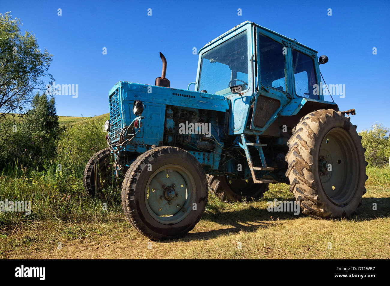 Blue wheeled agricultural tractor, dusty and rusty Stock Photo - Alamy
