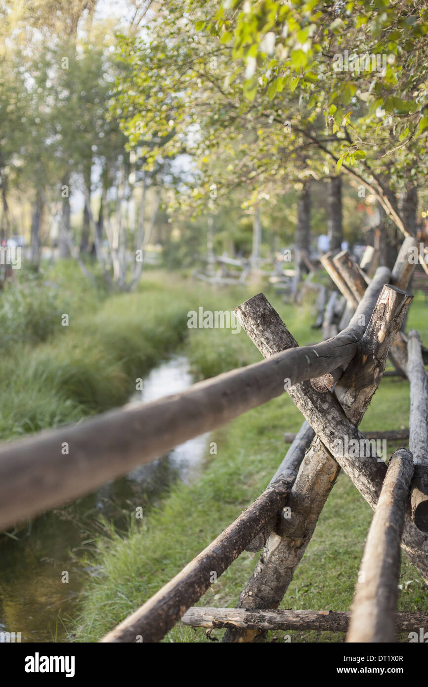 A rural scene view over a fence made of wooden posts A small stream ...