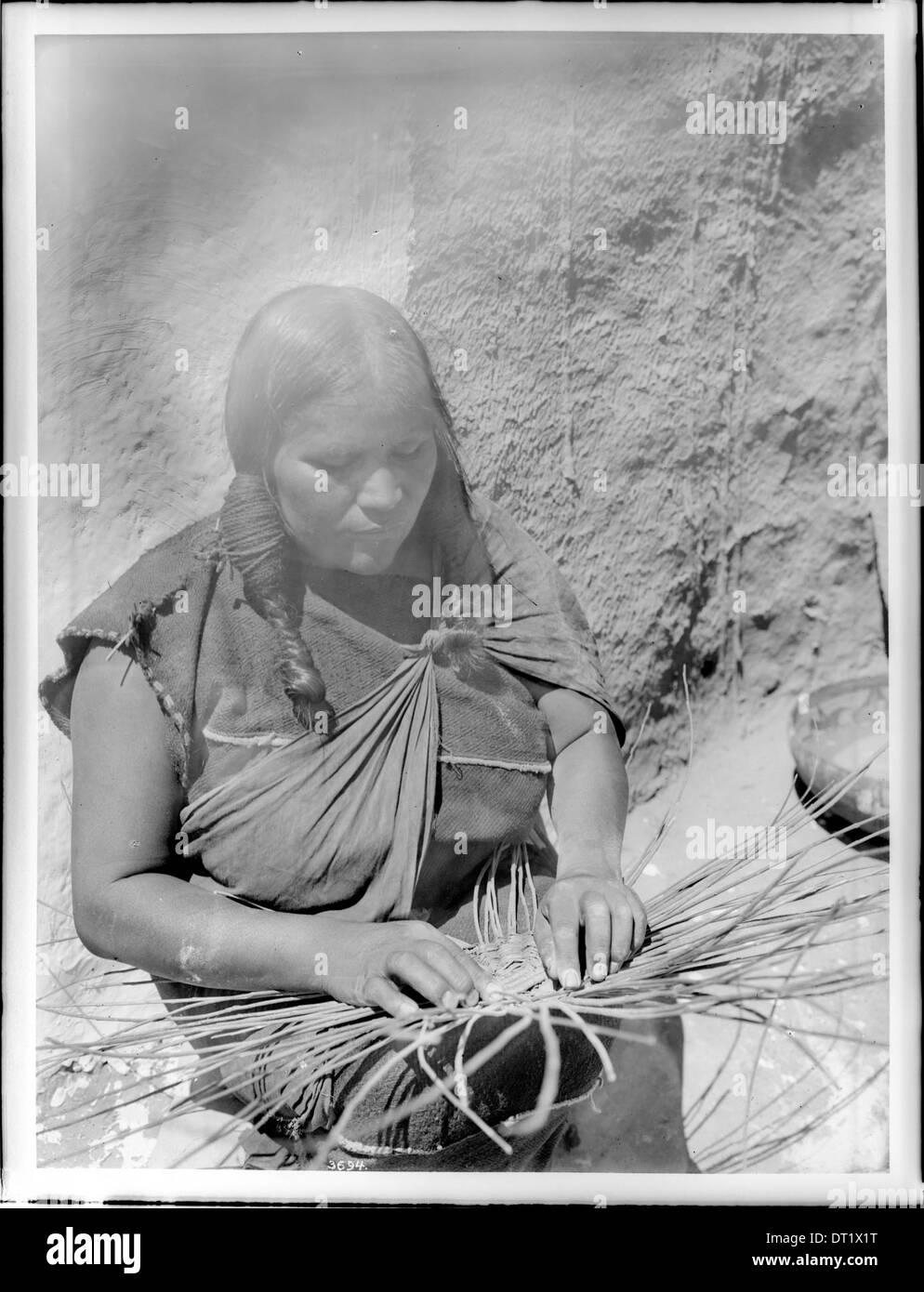 This photograph depicts a Hopi Indian woman engaged in basket weaving ...