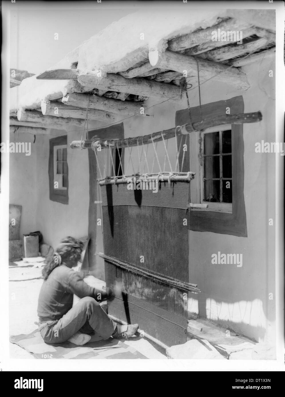 Hopi man (from his right side) weaving a rug, in the village of ...