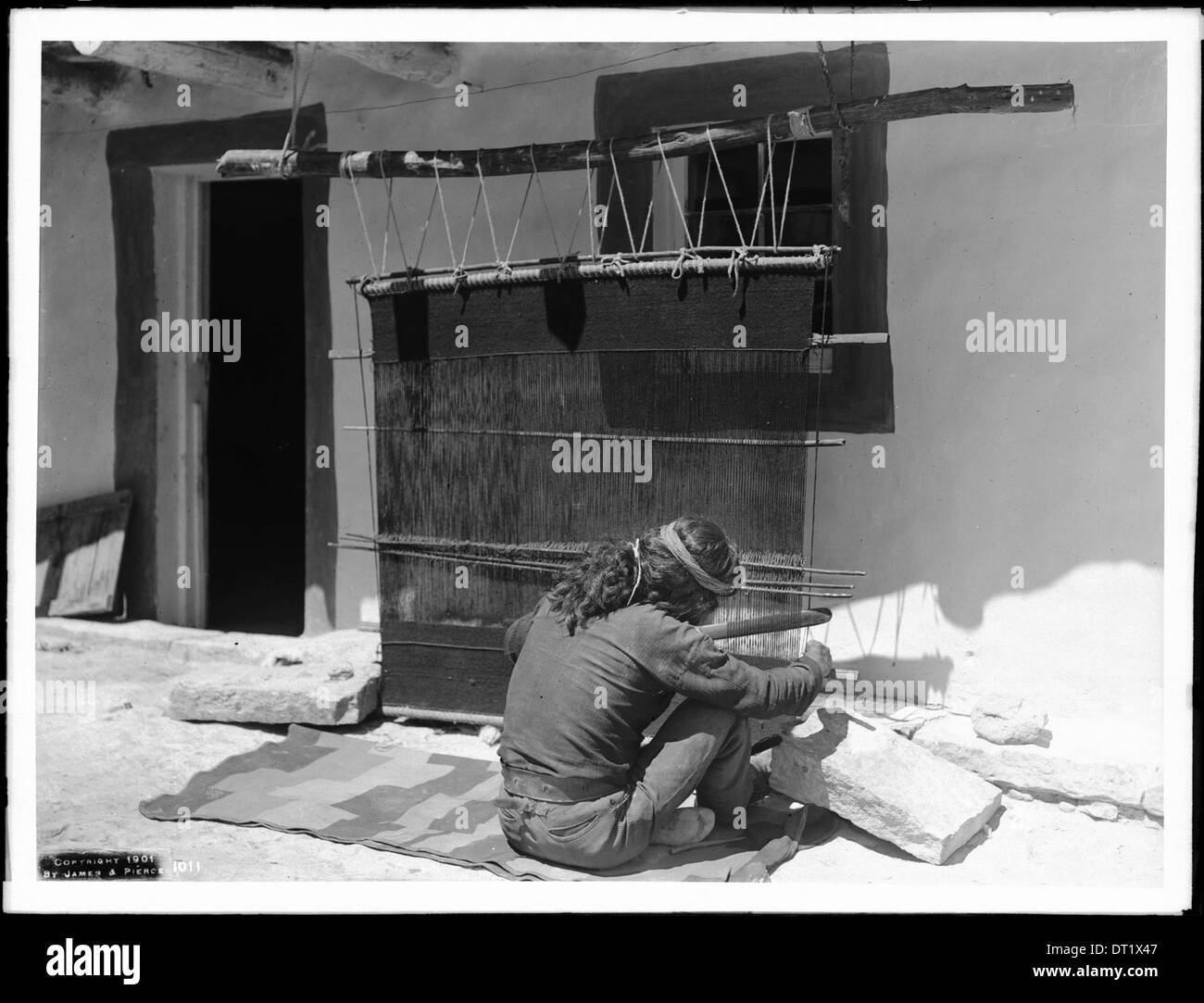 A Hopi man is shown weaving cloth for a woman’s dress in the village of ...