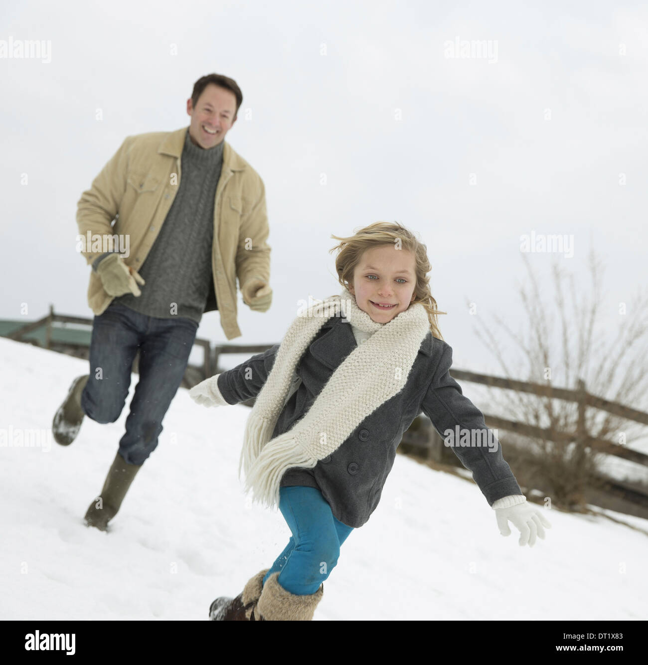 A man chasing a young girl in the snow Farm in winter Stock Photo - Alamy