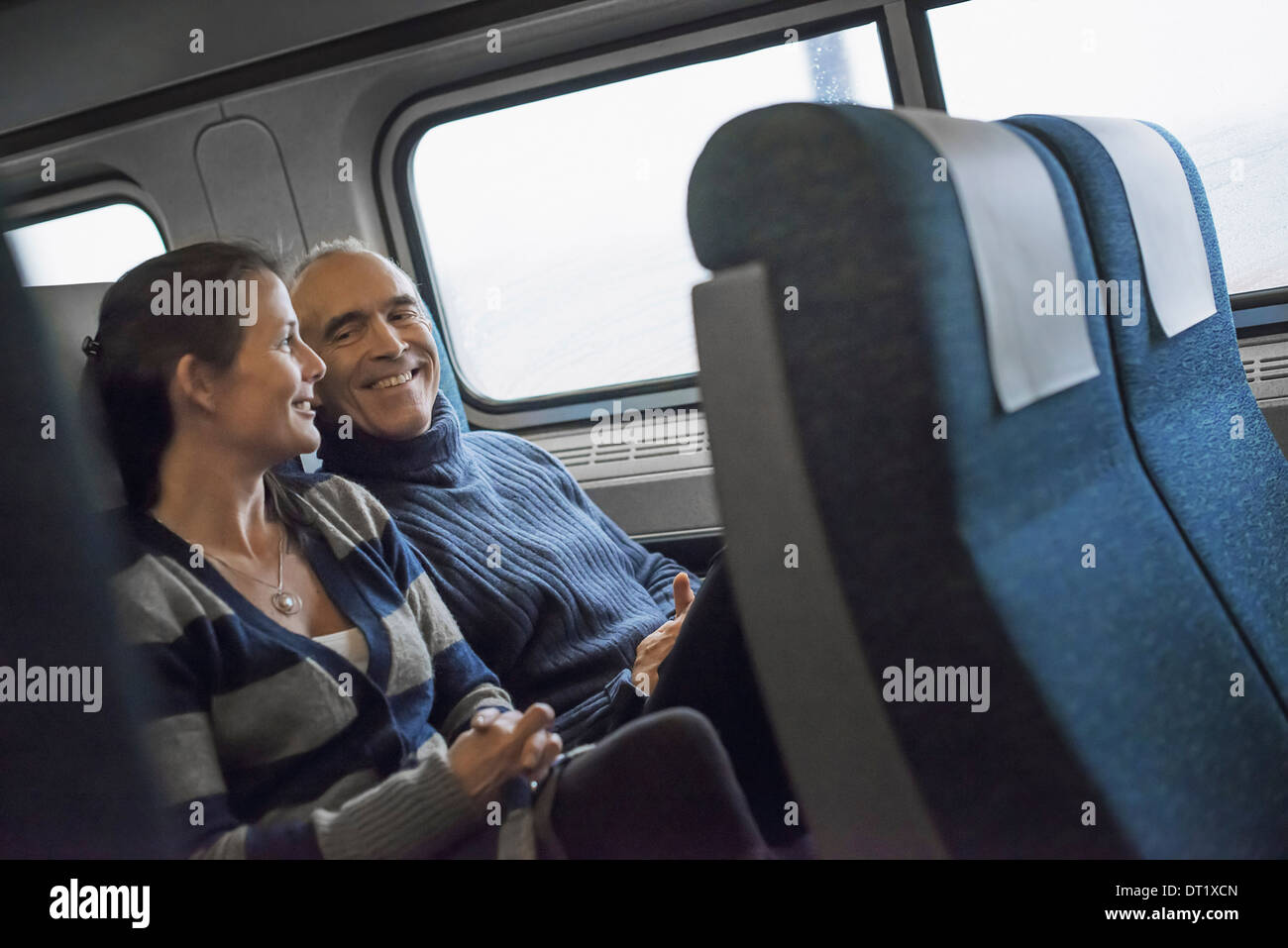 Two people sitting in a railway carriage smiling Taking a train journey ...