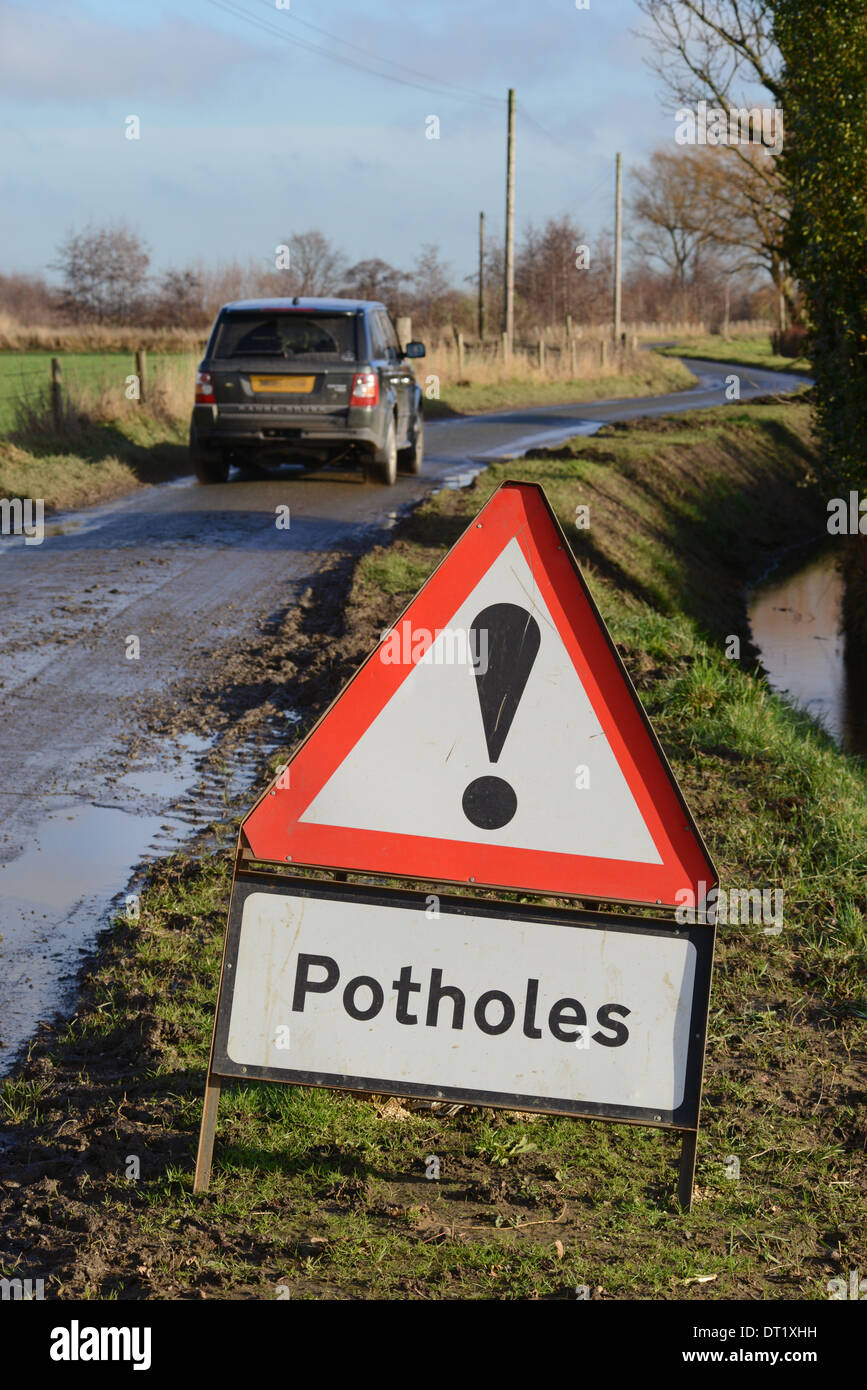 four wheel drive vehicle passing warning sign of potholes on country ...