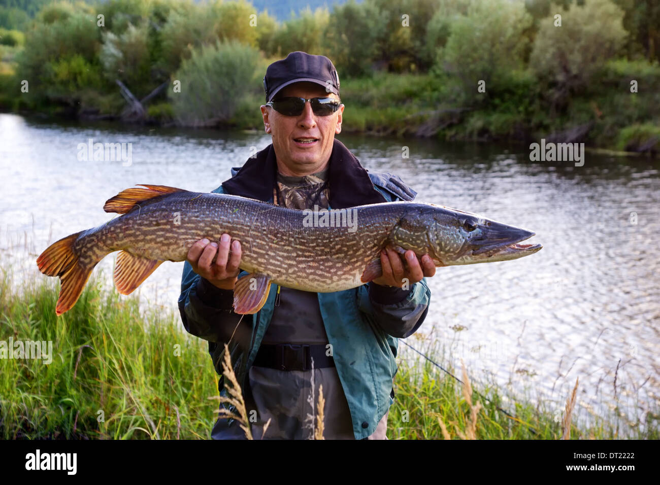 Fisherman with pike fish on the shore of river Uur in northern Mongolia ...