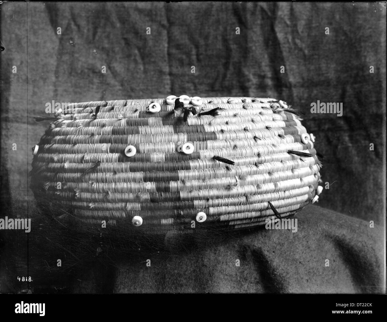 A photograph showing a Native American basket displayed in front of a ...
