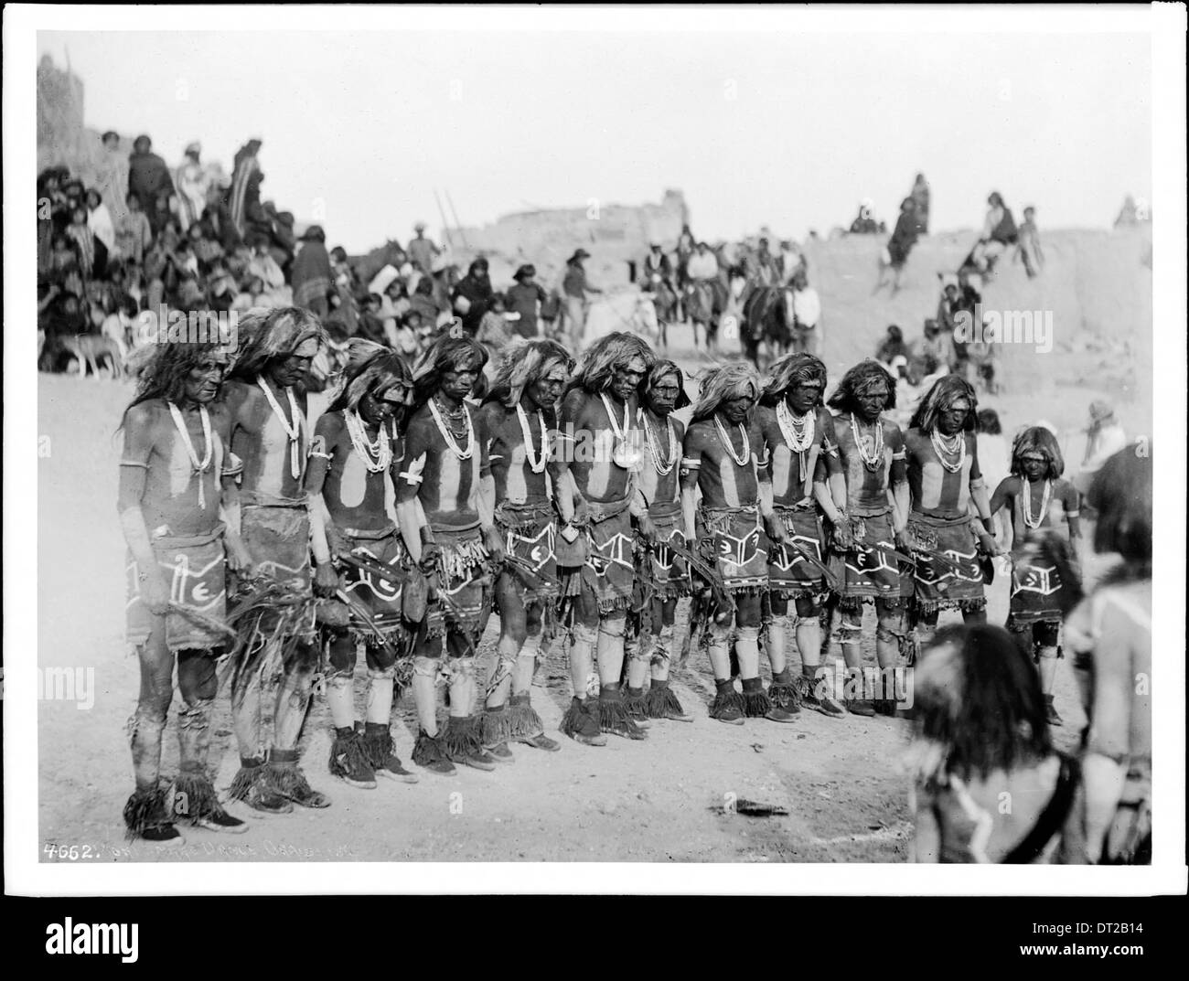 A line of twelve Hopi snake priests singing and praying before a kiva ...