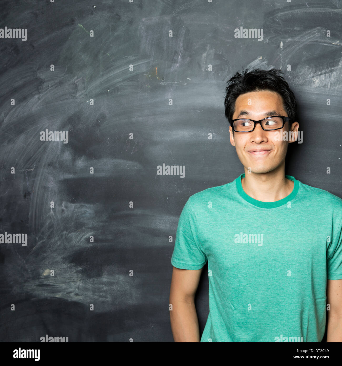 Portrait of a happy Asian/Chinese man standing next to a blackboard ...