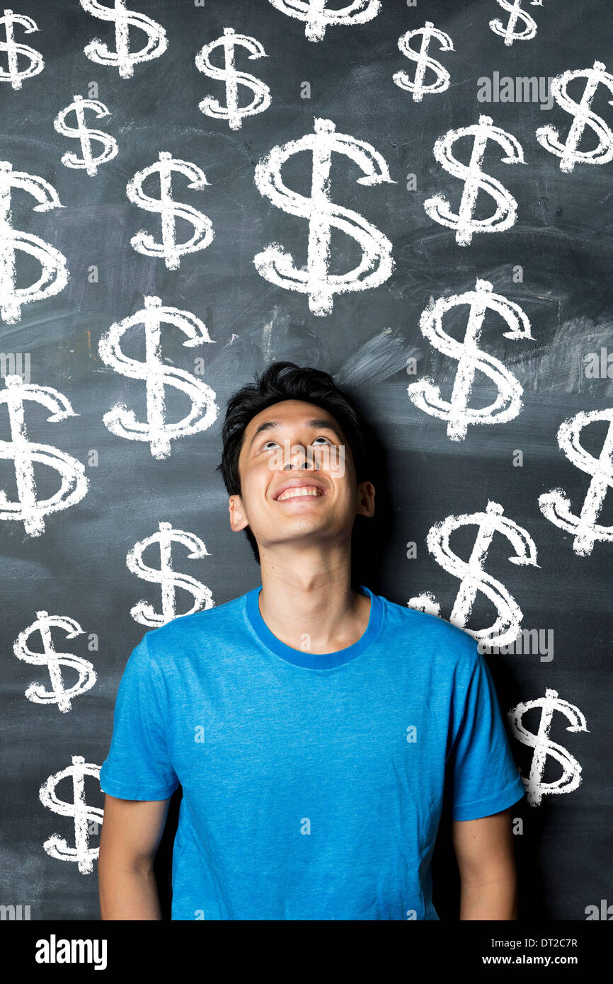 Happy Asian man standing in front of lots of dollar sign written on a ...