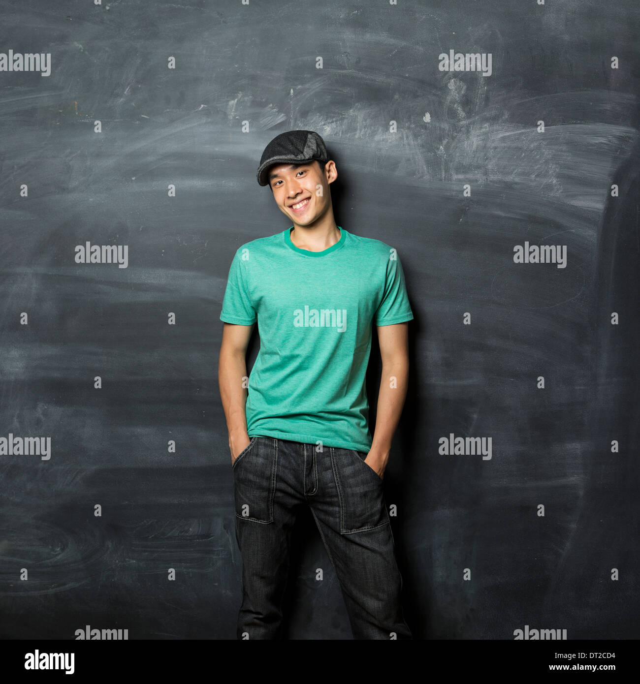 Portrait of a happy Asian/Chinese man standing next to a blackboard ...