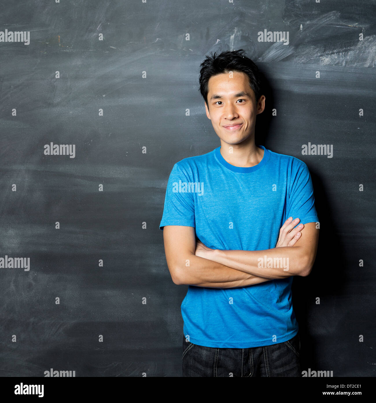 Portrait of a happy Asian/Chinese man standing next to a blackboard ...