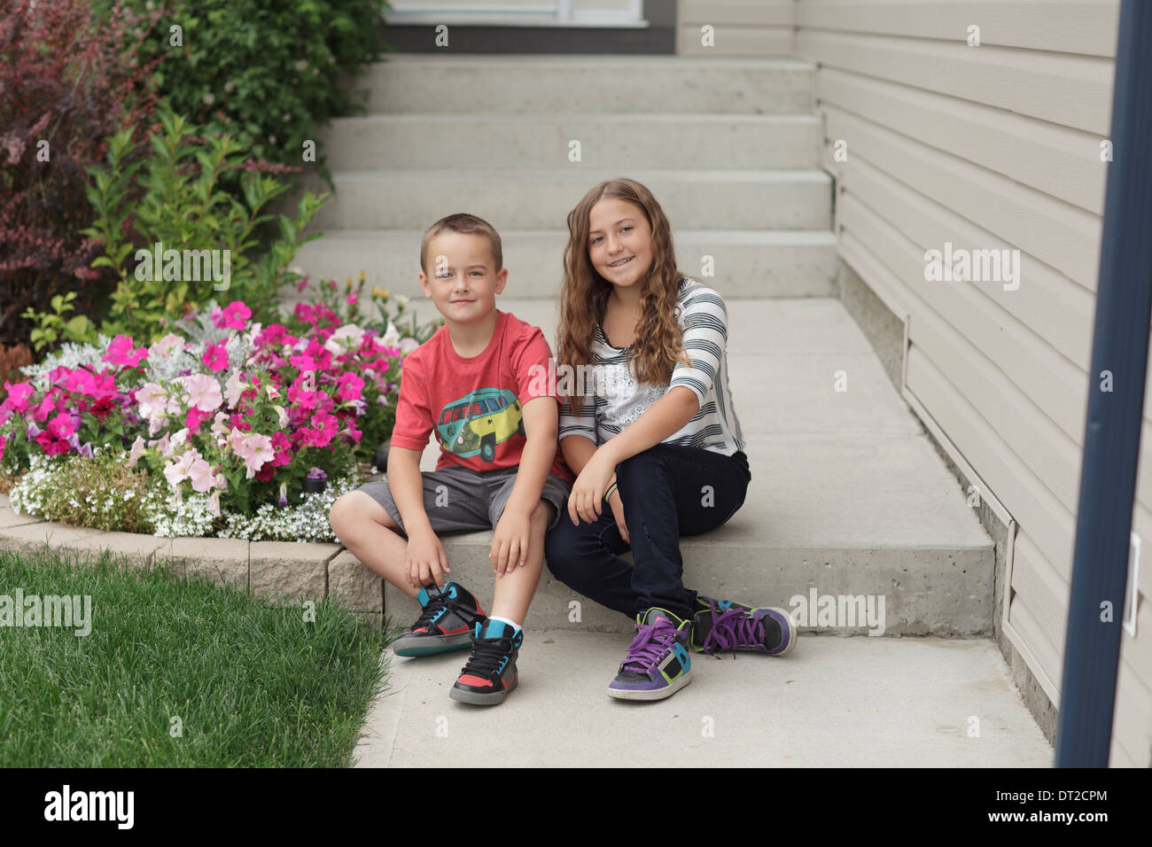 siblings sitting together on a step Stock Photo - Alamy