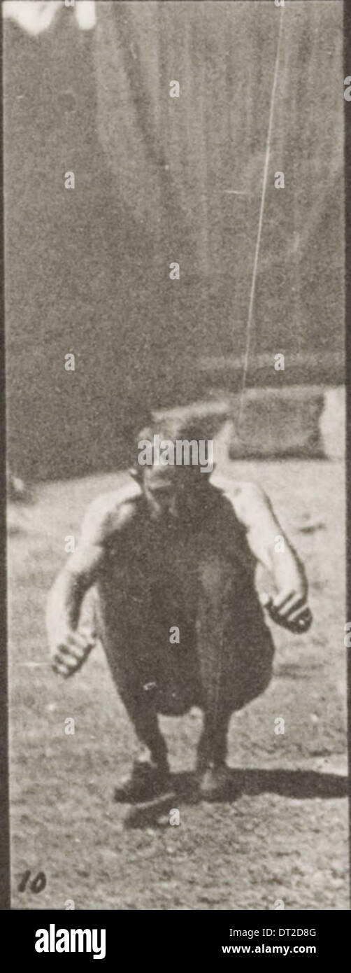 A man dressed in a pelvis cloth is performing a standing broad jump ...