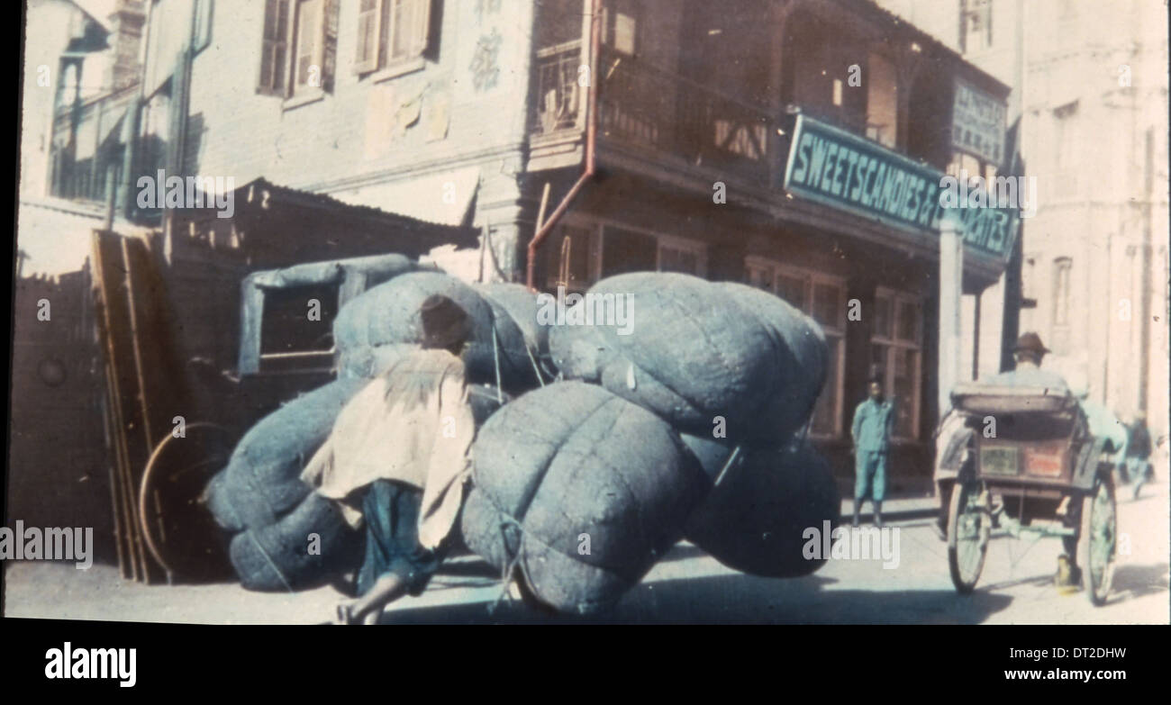 A man pushing a large load of cotton bales in a wheelbarrow in Shanghai ...
