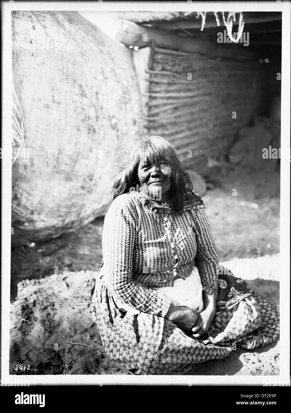 A Mojave Indian woman is seated in front of a ramada, an open shelter ...
