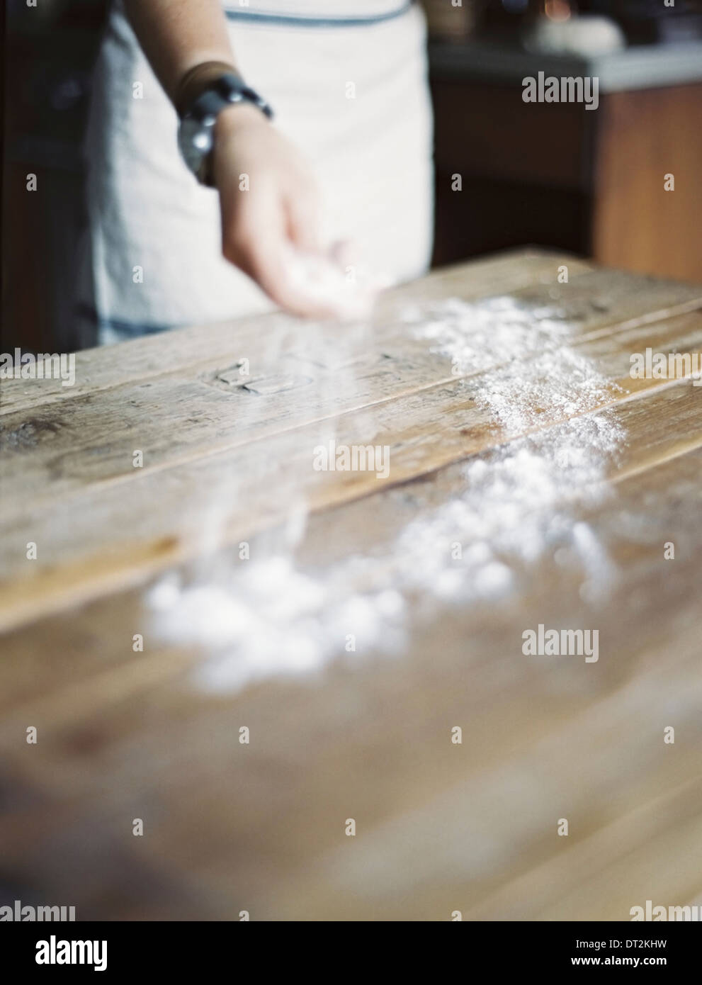A domestic kitchen A woman cooking Spreading flour across a tabletop ...