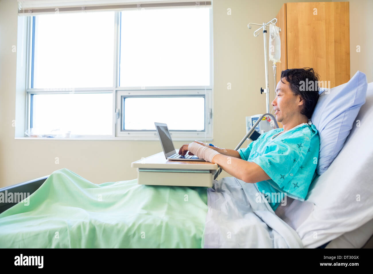Patient Using Laptop On Hospital Bed Stock Photo - Alamy