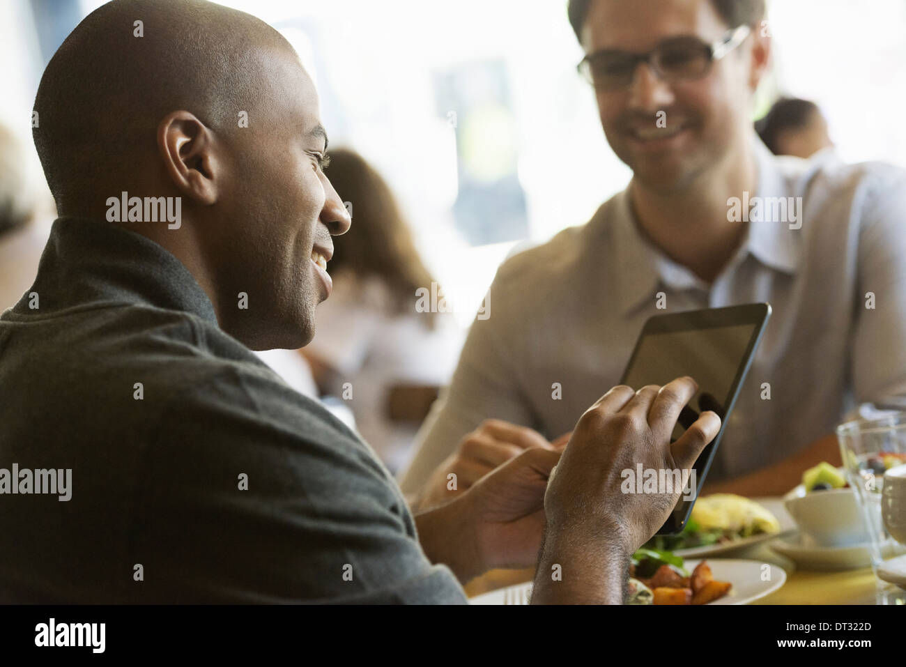 Two men seated at a cafe table having a meal Stock Photo - Alamy
