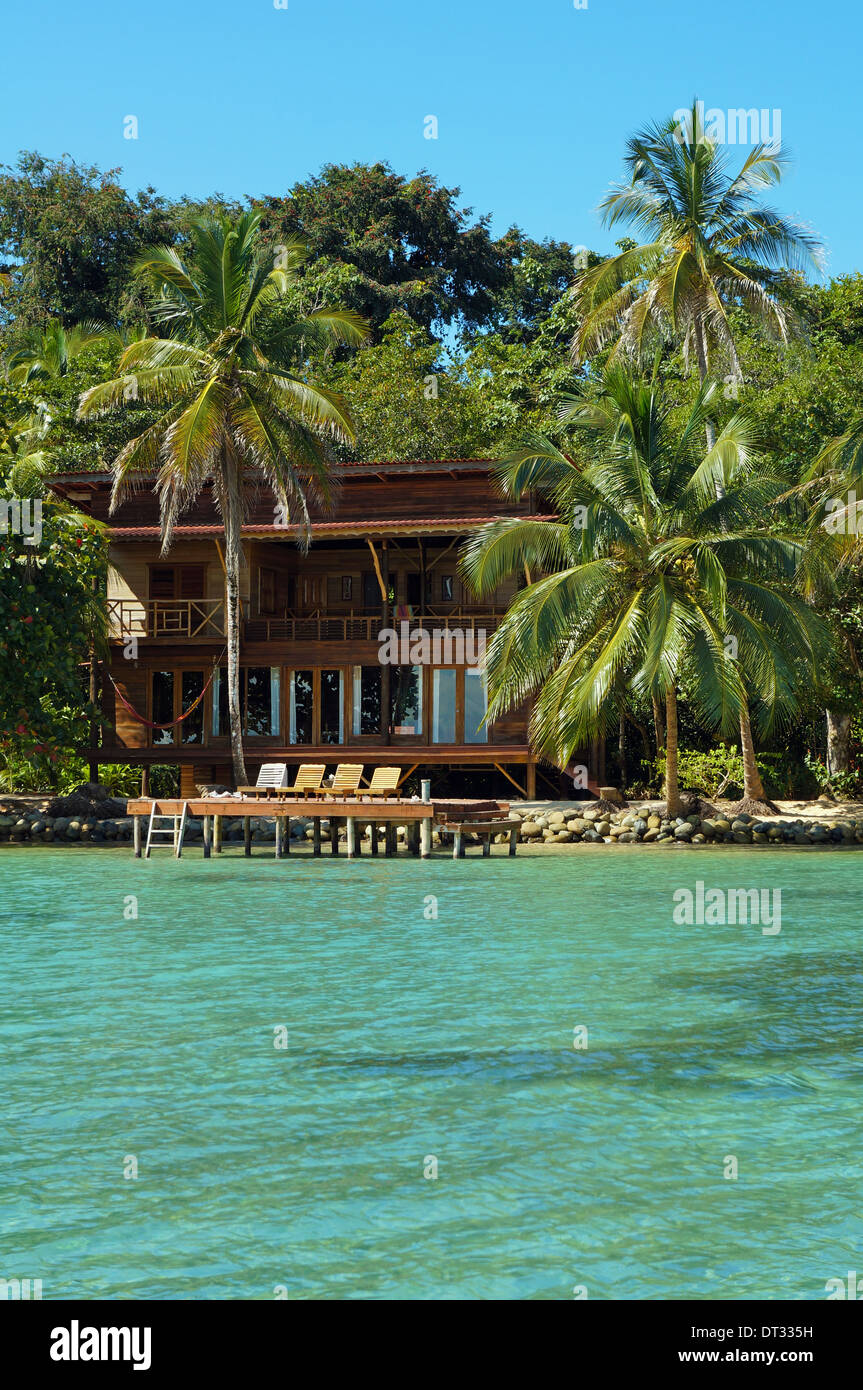 Tropical seaside house with coconut trees and a dock with lounger ...