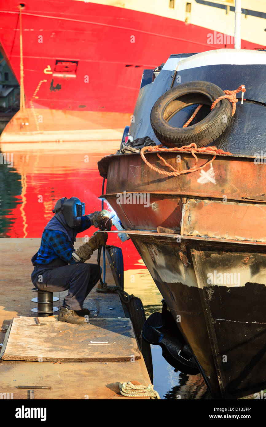 Welder in a protective mask when welding the hull of the ship Stock ...
