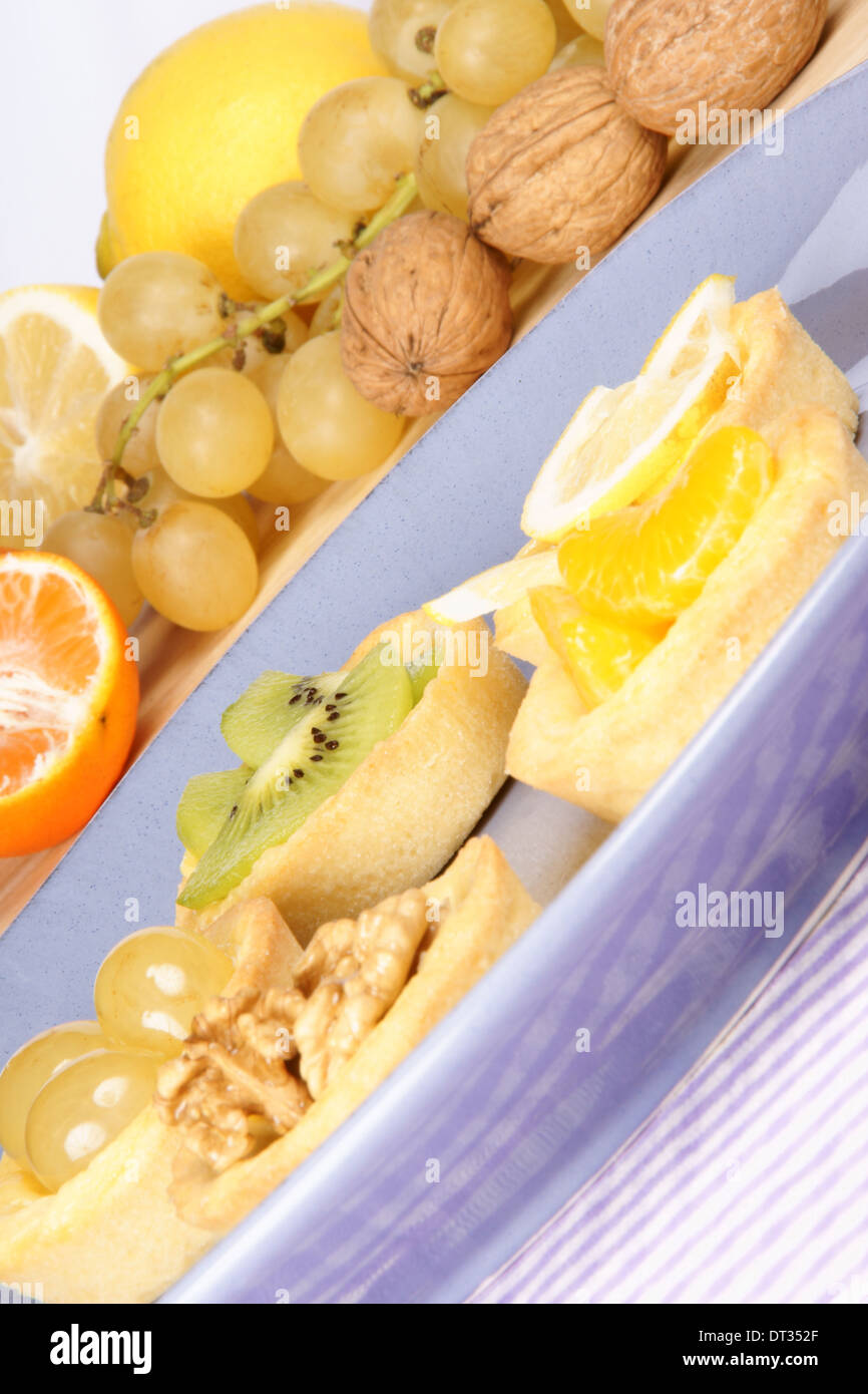 Assorted mini fruit tarts on a ceramic plate with fruit in the ...
