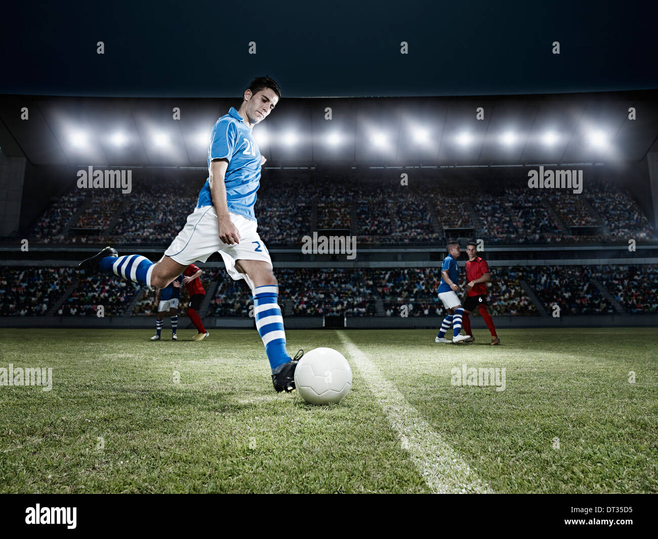 Soccer player kicking ball on field Stock Photo - Alamy
