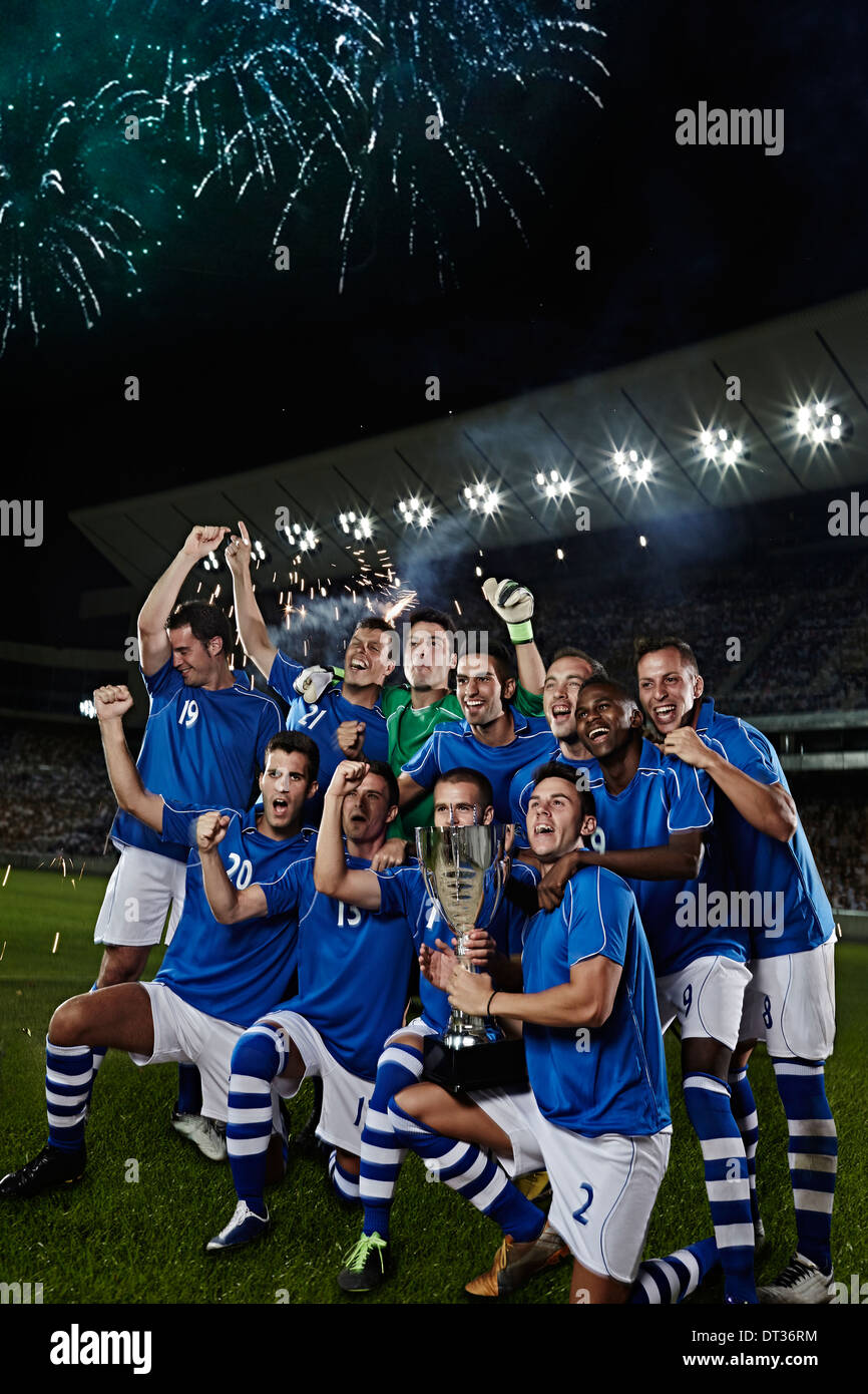Soccer team cheering with trophy on field Stock Photo - Alamy