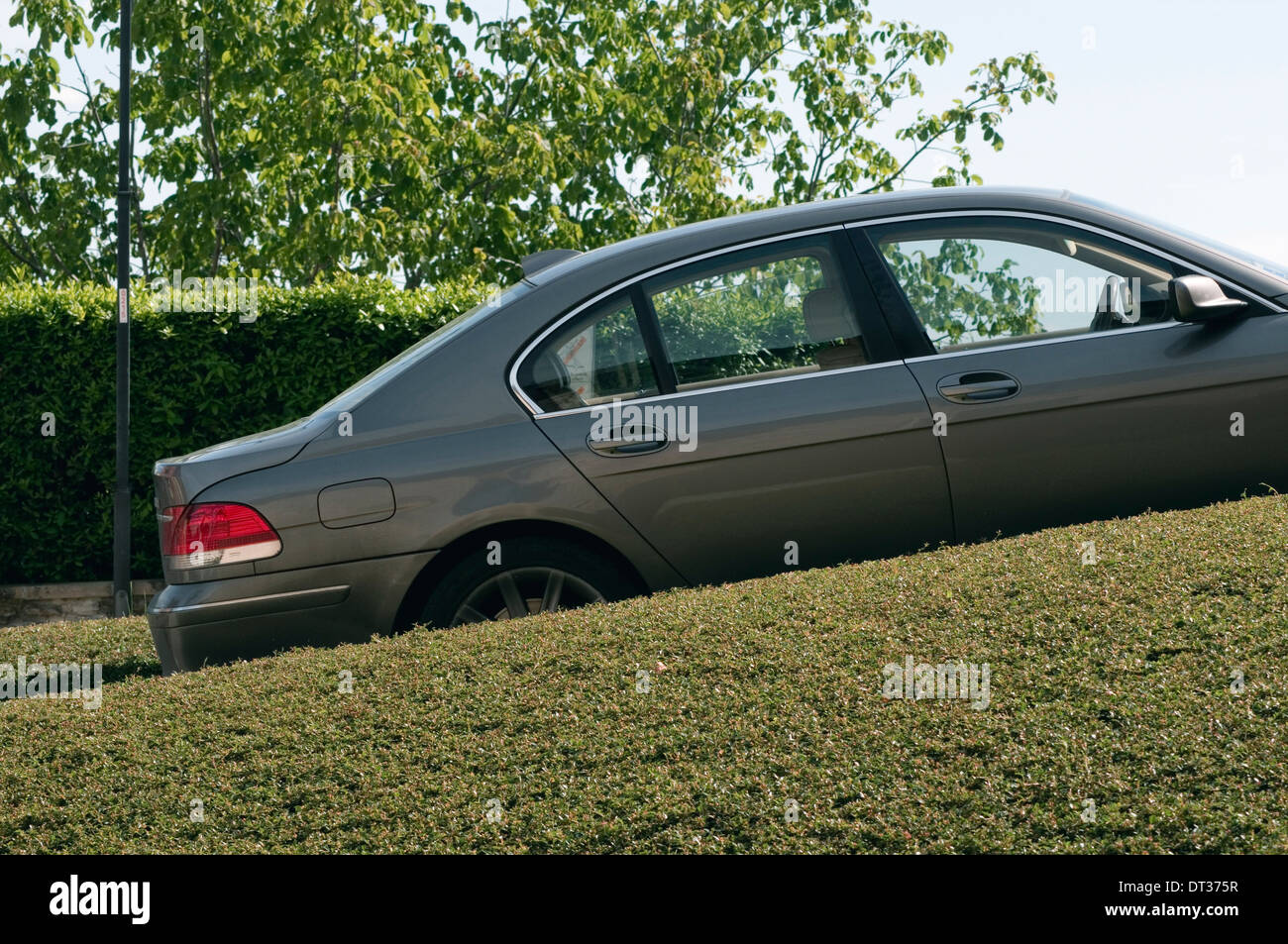 Car parked uphill and garden hedge Stock Photo - Alamy