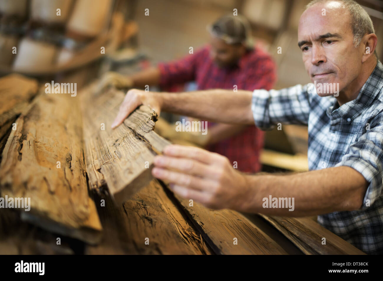 A reclaimed lumber workshop. A group of people working. A man measuring ...
