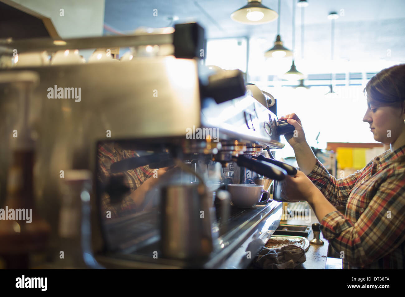 A person, barista making coffee, and frothing milk using a steam pipe ...