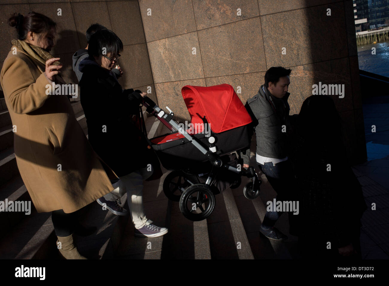A mother and father carry their child's pushchair down steep steps in ...
