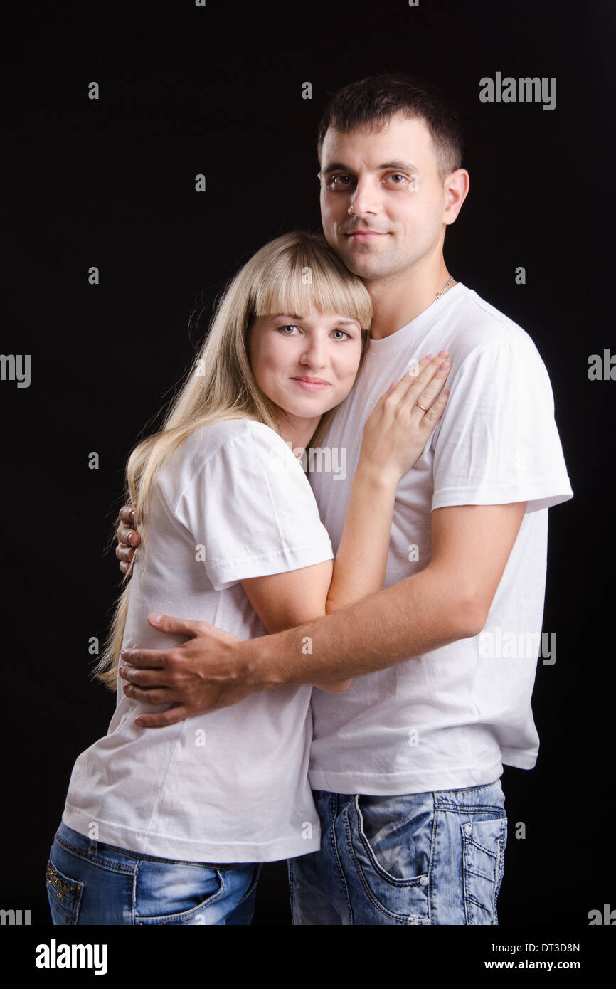 A half-length portrait of a young couple. Guy hugging a girl back ...