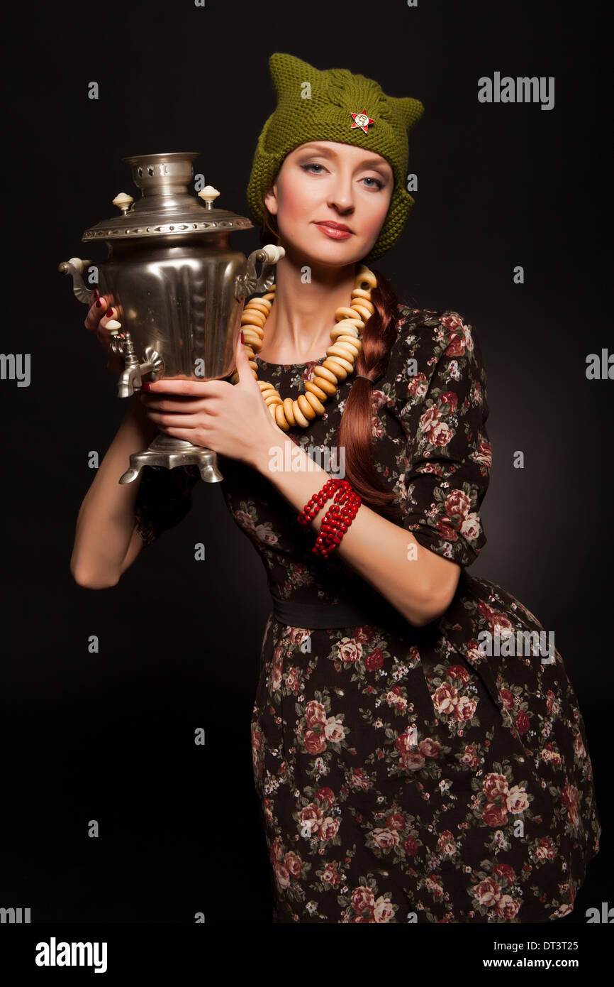 Girl in soviet retro style posing with samovar. Girl with a green cap ...