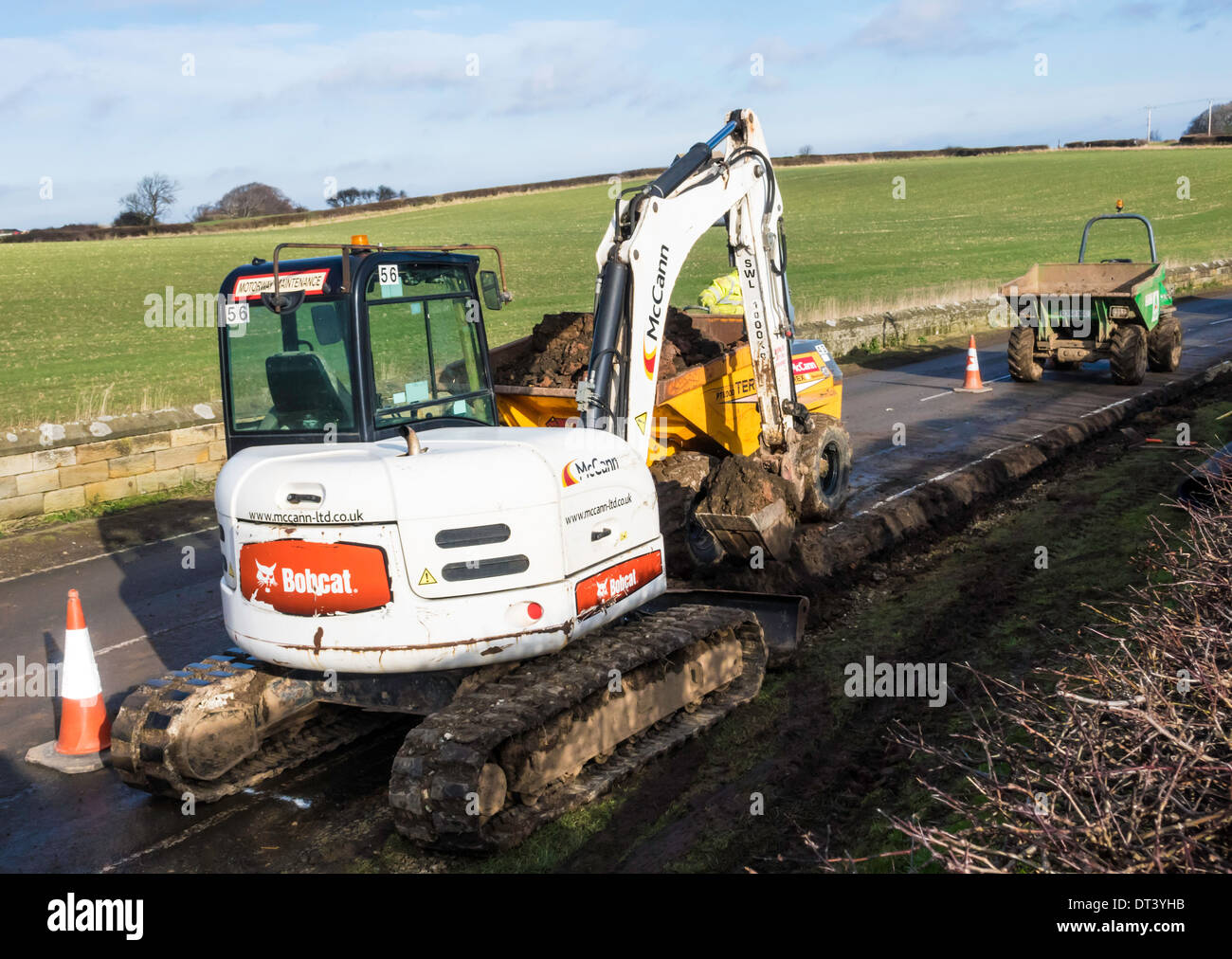 A Bob Cat backhoe excavator and Dumper Truck excavating a pipe trench ...