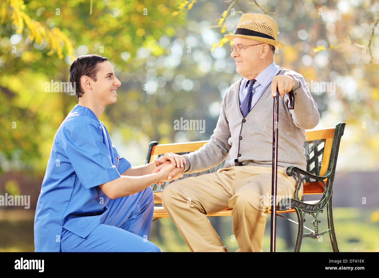 Healthcare professional helping senior man sitting on a bench outside ...