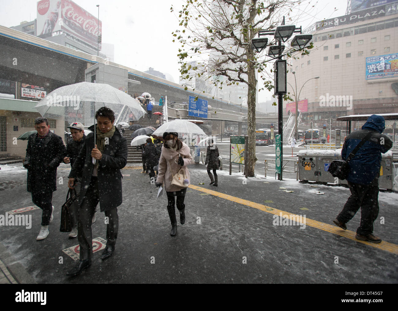 Tokyo, Japan. 8th Feb, 2014. Pedestrians walk under snow near a train ...