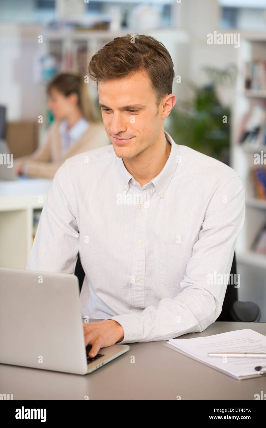 Man Cheerful desk laptop young colleagues Stock Photo - Alamy
