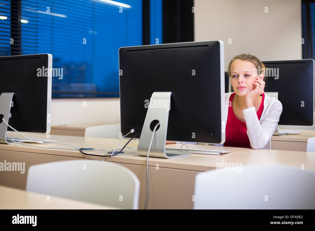 Pretty, young female college student using a desktop computer/pc in a ...