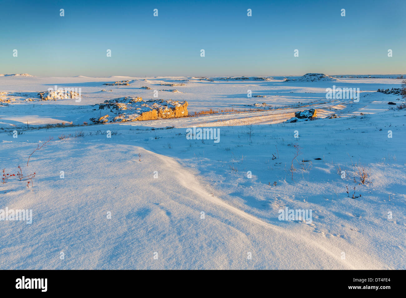 prairie with rock outcroppings covered by snow at sunset, northern ...