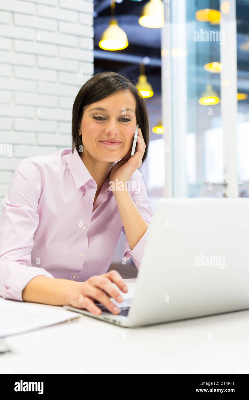 Brunette businesswoman on the mobile phone using computer in office ...
